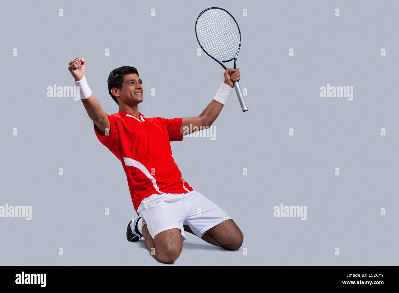Happy male tennis player celebrating victory isolated over gray ...
