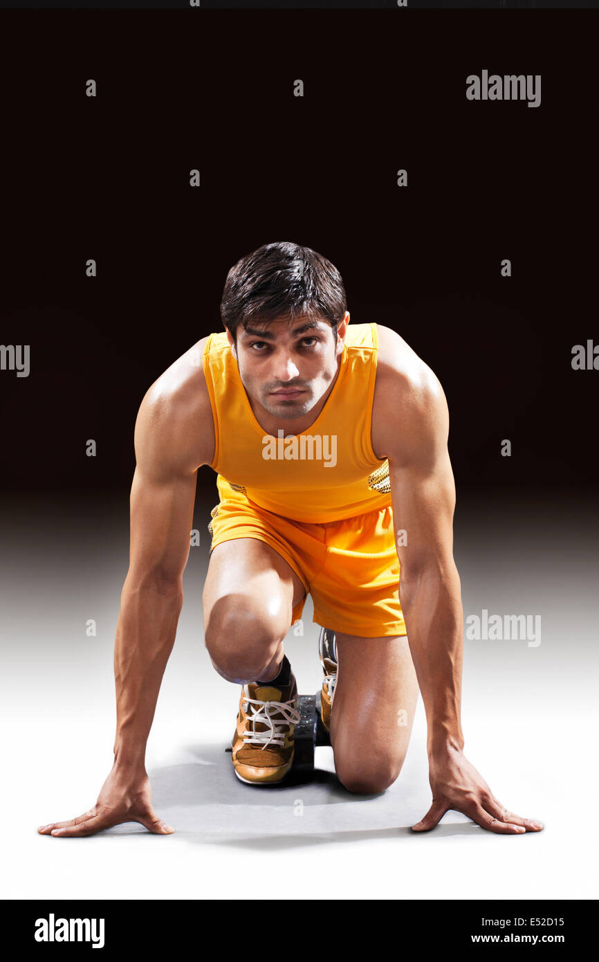 Young male runner ready to sprint out of starting blocks isolated over ...