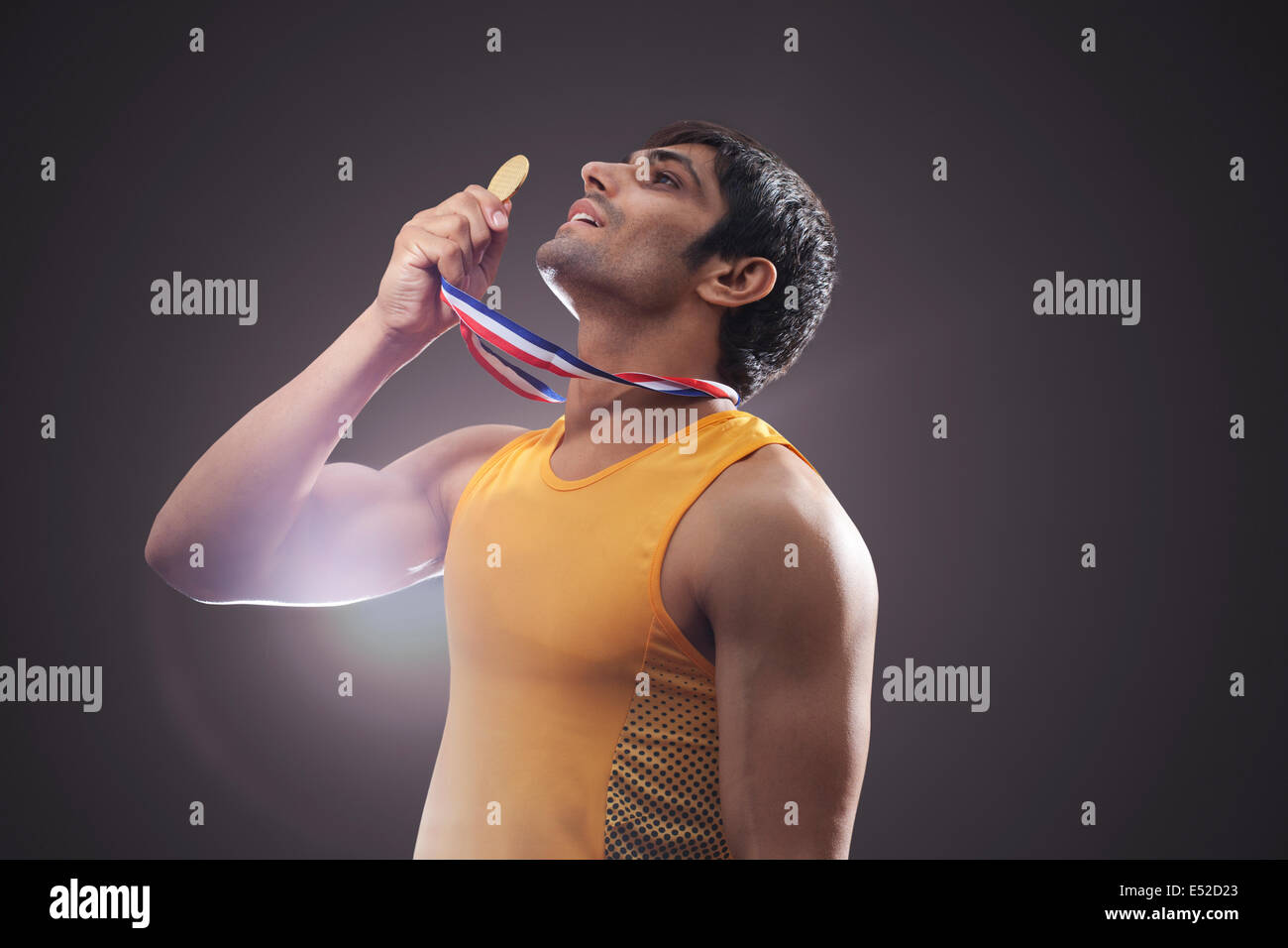 Side view of young male runner holding medal over black background ...
