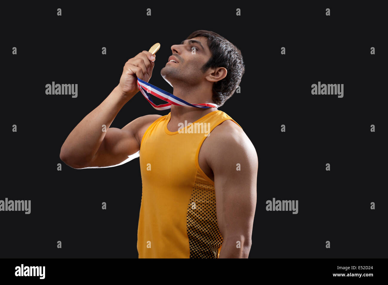Side view of young male runner holding gold medal isolated over black ...