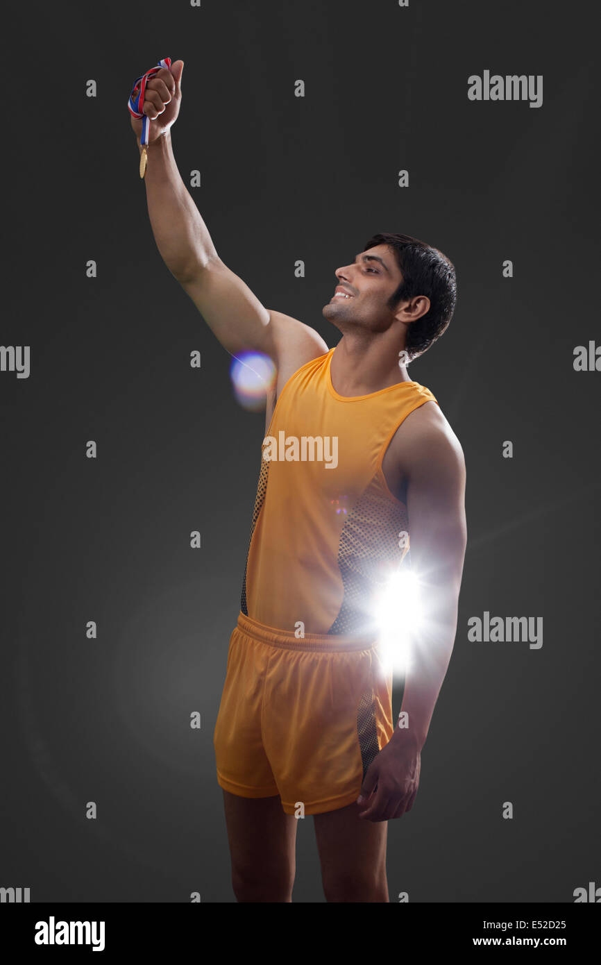 Happy male runner holding gold medal isolated over black background ...
