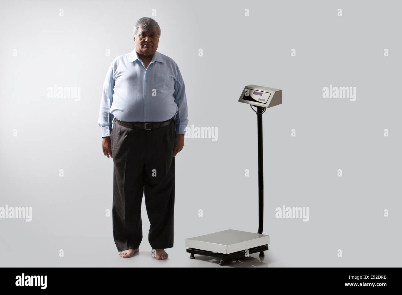 Portrait of obese man with weighing scale Stock Photo - Alamy