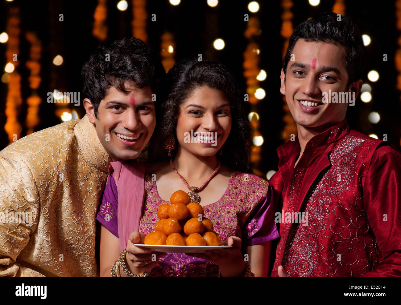 Portrait of two men and a woman holding sweets Stock Photo - Alamy