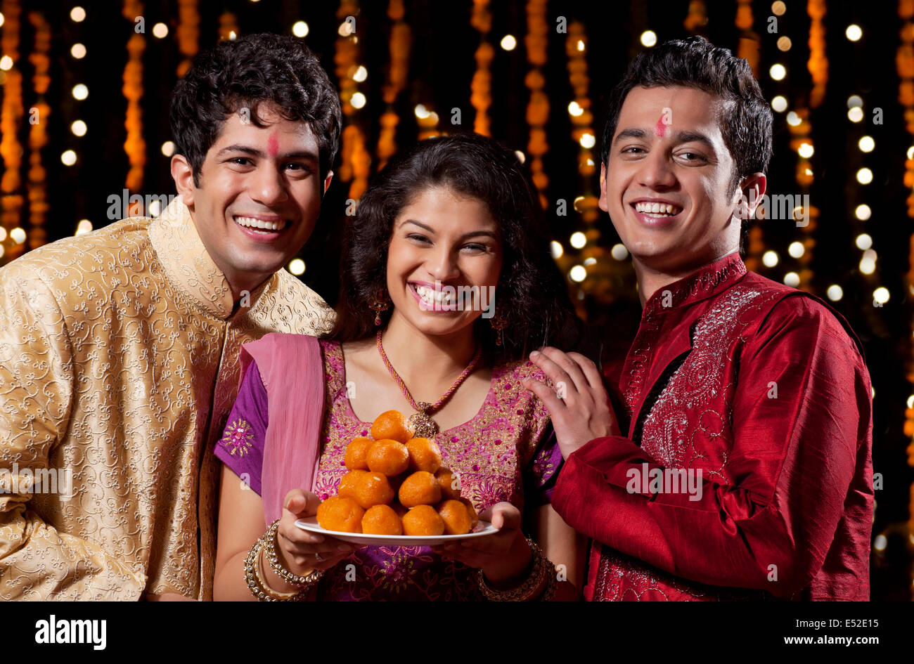 Portrait of two men and a woman holding sweets Stock Photo - Alamy