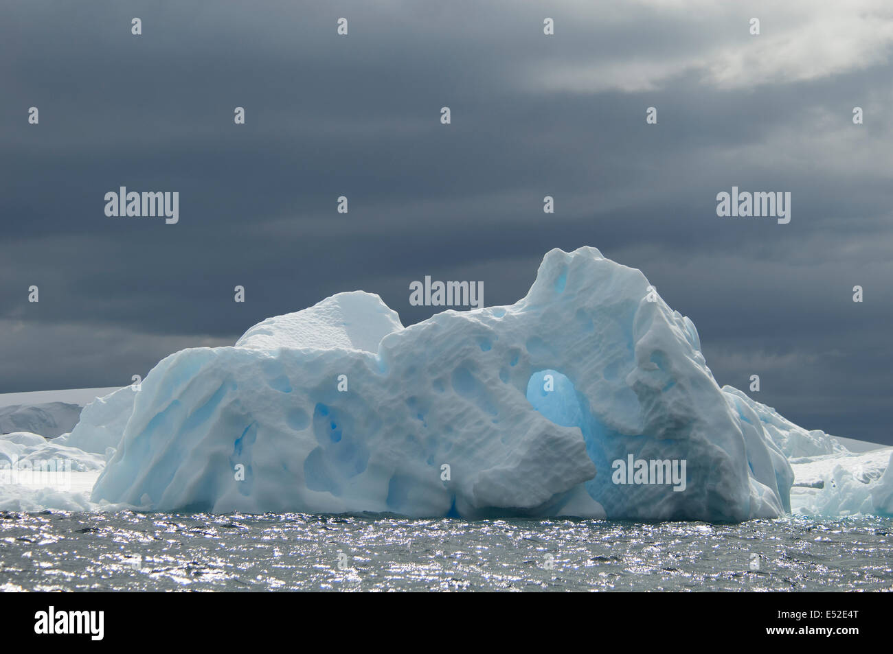 An iceberg on the waters of the Southern Ocean under a stormy grey sky ...