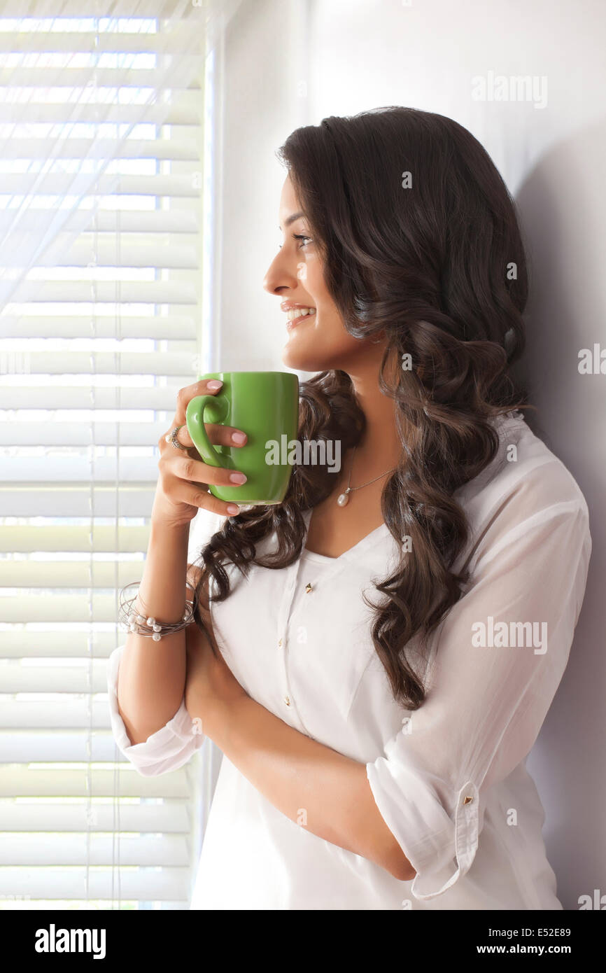 Woman with a mug of tea thinking Stock Photo - Alamy