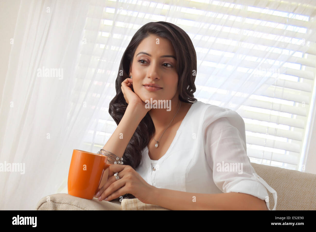 Woman with a mug of tea thinking Stock Photo - Alamy
