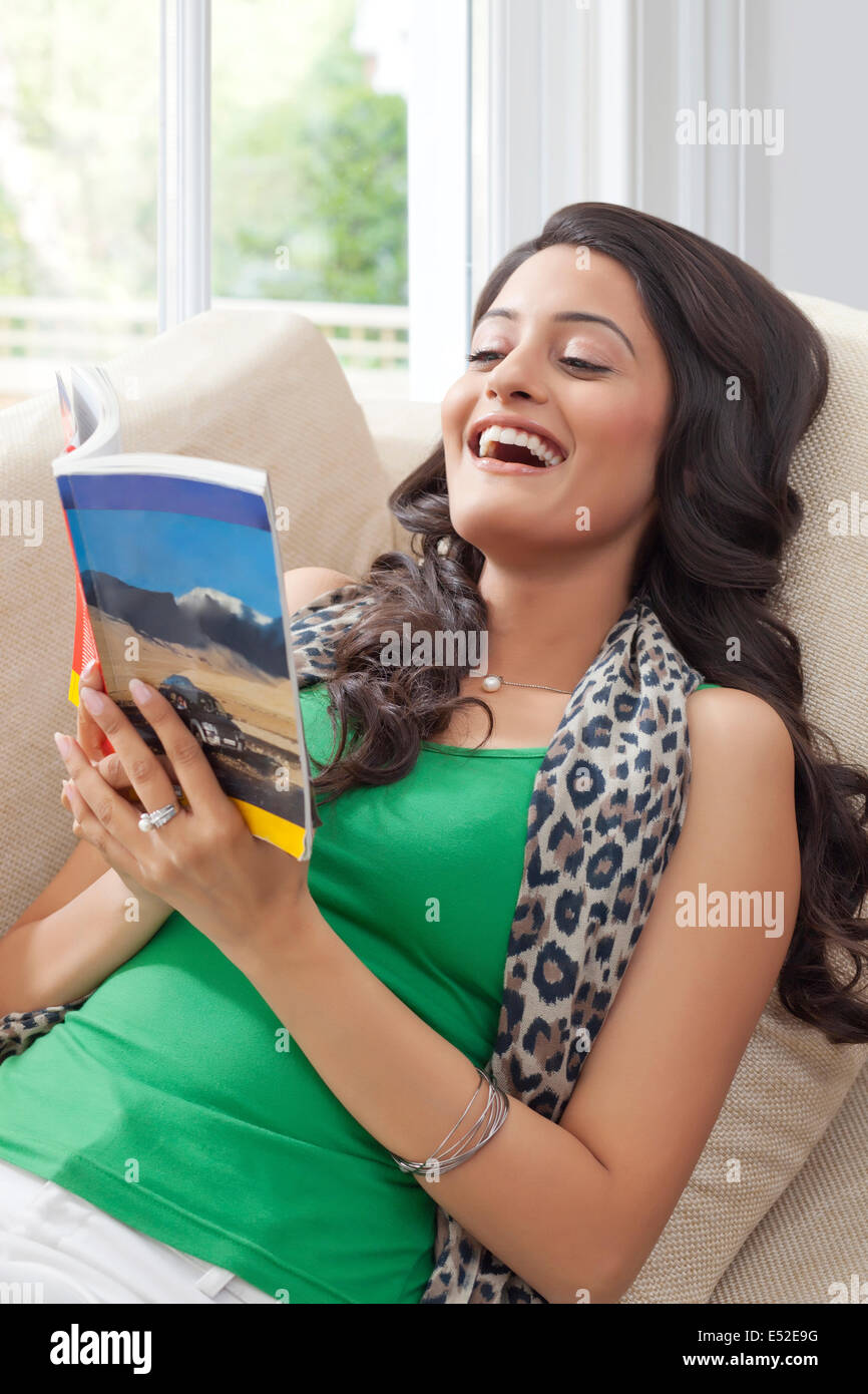 Woman laughing while reading a book Stock Photo - Alamy