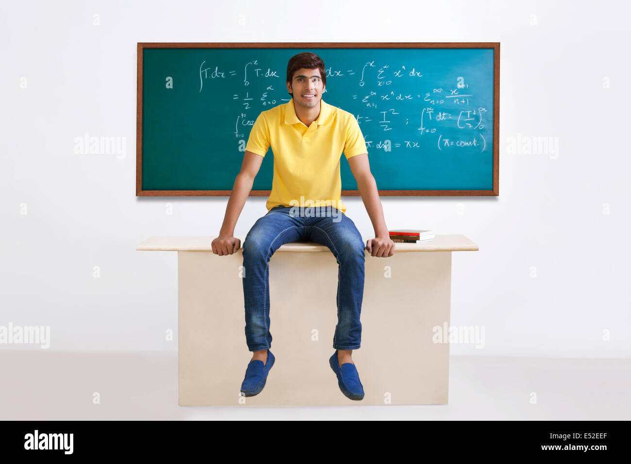 Portrait of a college student sitting on a table smiling Stock Photo ...