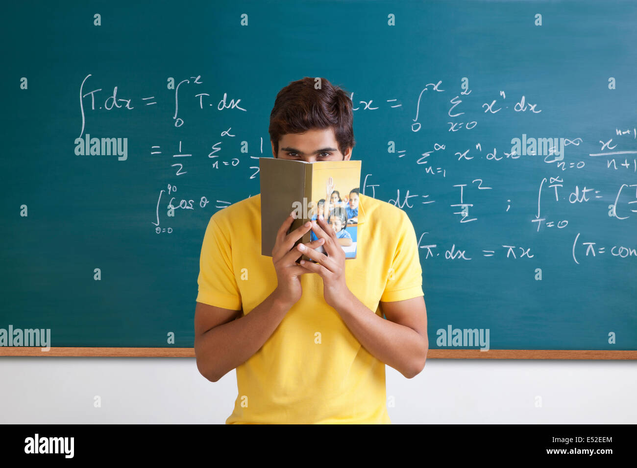 College student hiding his face with a book Stock Photo - Alamy