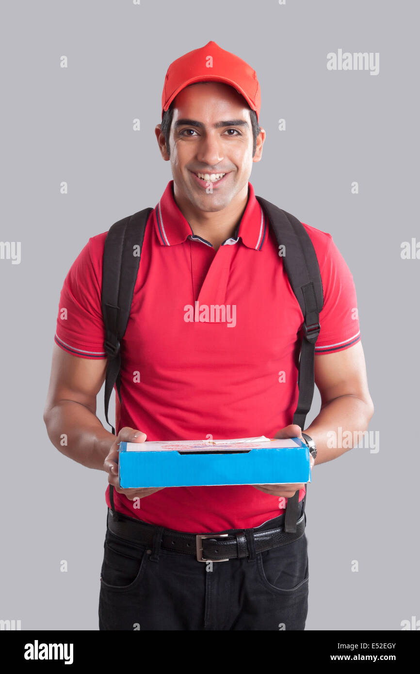 Portrait of confident pizza delivery man against gray background Stock ...