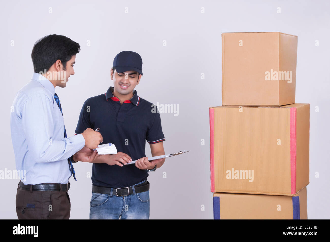 Young delivery man delivering package to businessman against gray ...