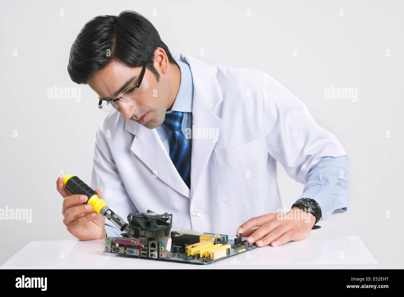 Handsome technician working on computer part against gray background ...