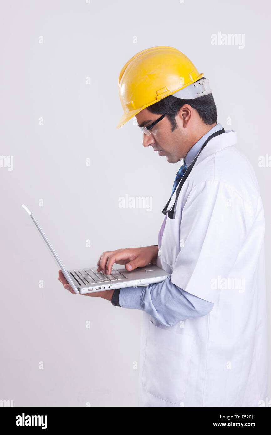 Side view of technician using laptop against gray background Stock ...