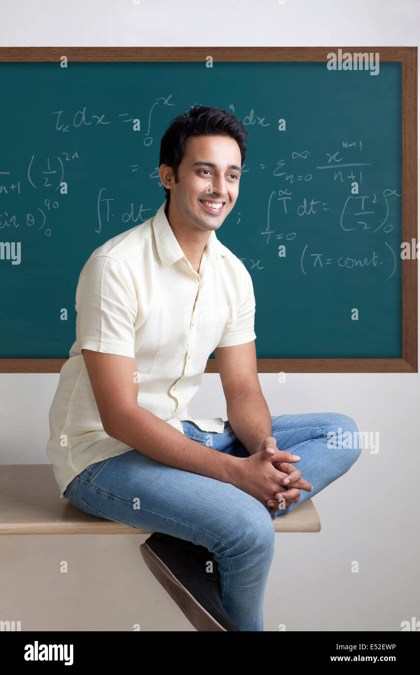 College student sitting on a table smiling Stock Photo - Alamy