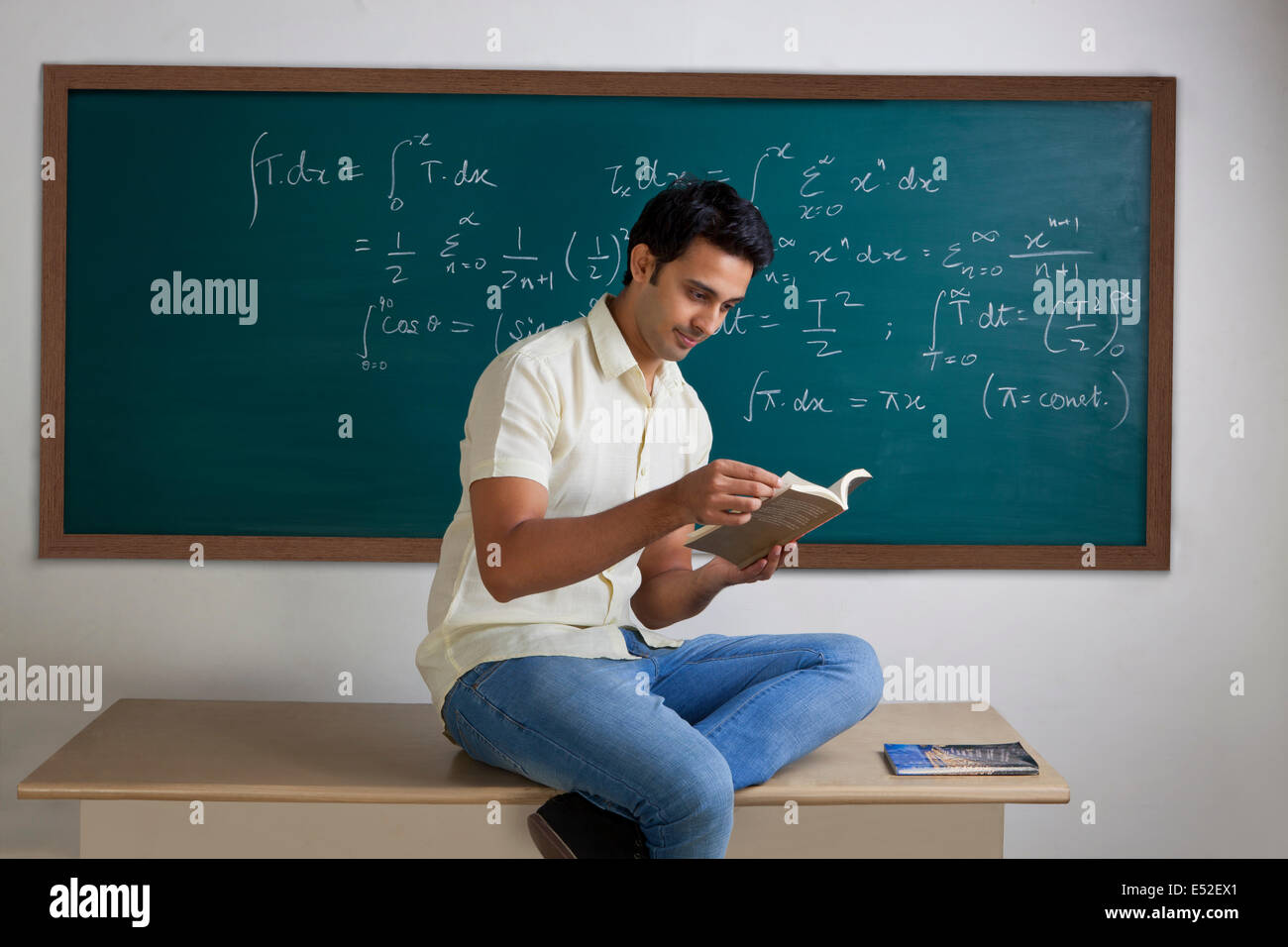 College student sitting on a table reading a book Stock Photo - Alamy