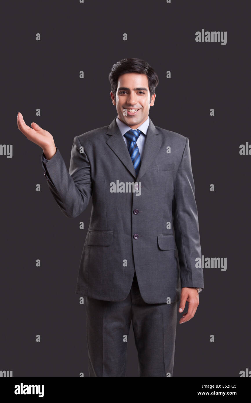 Portrait of confident businessman showing invisible product over black ...
