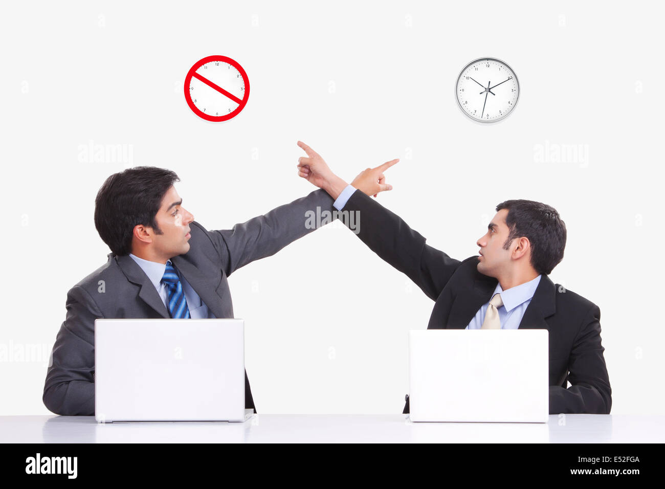 Businessmen using laptops while pointing at clocks against white ...