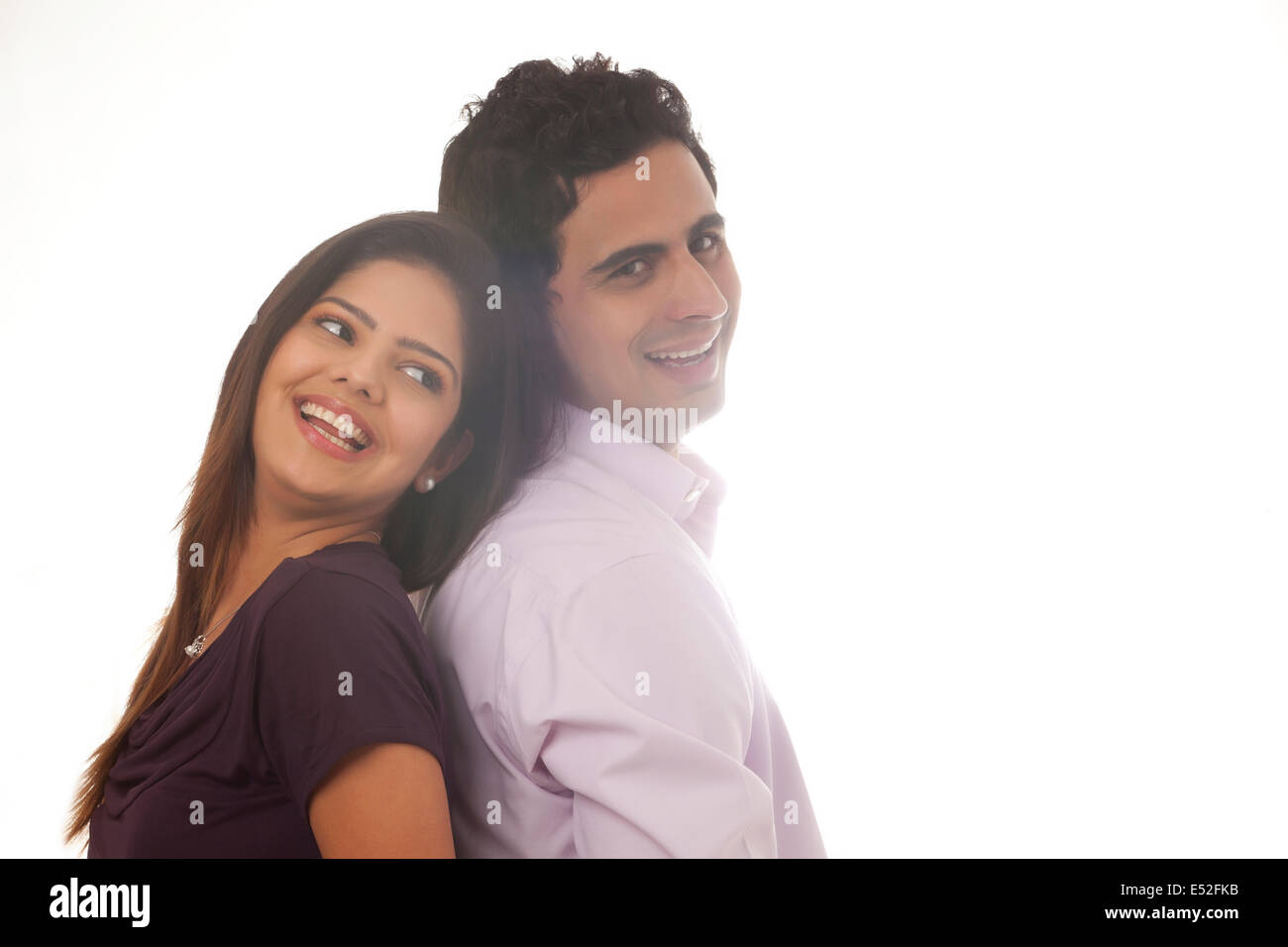 Couple standing back to back smiling Stock Photo - Alamy