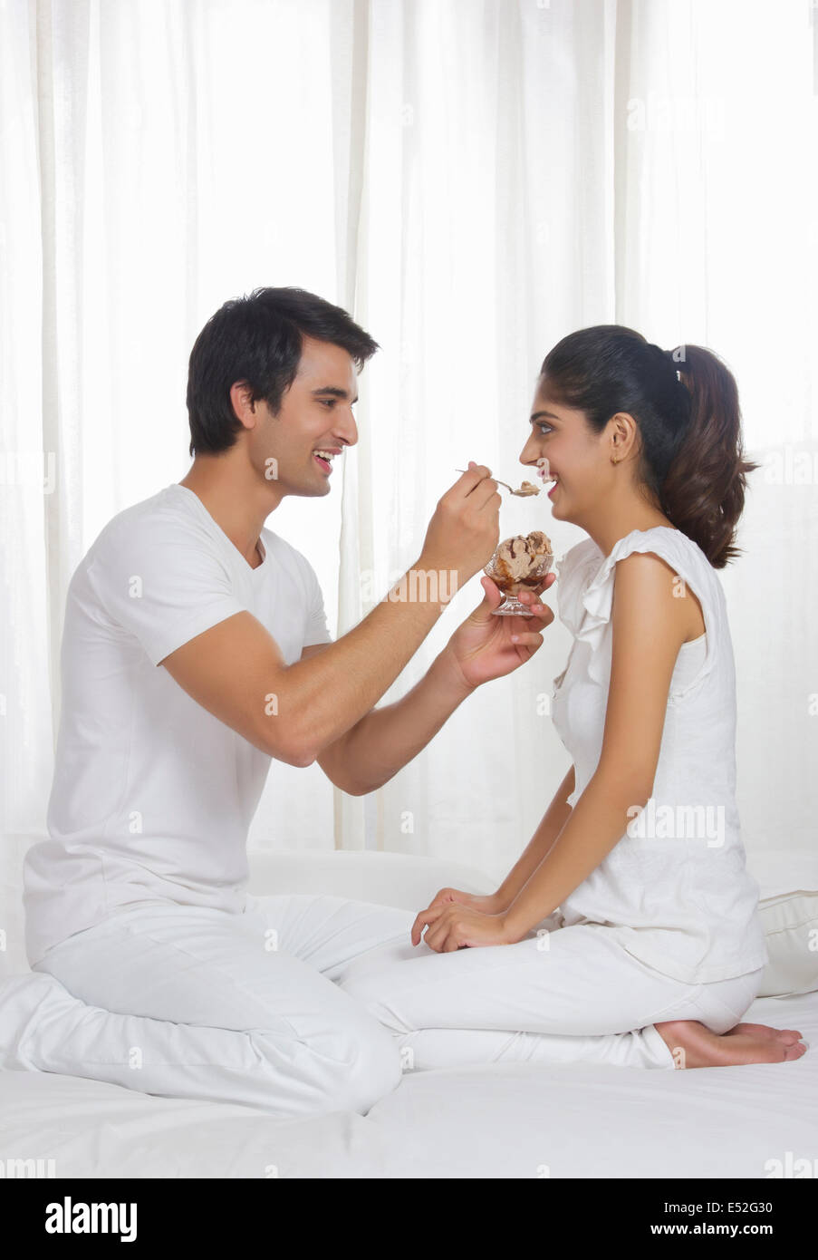Side view of young man feeding woman chocolate ice cream in bed Stock ...