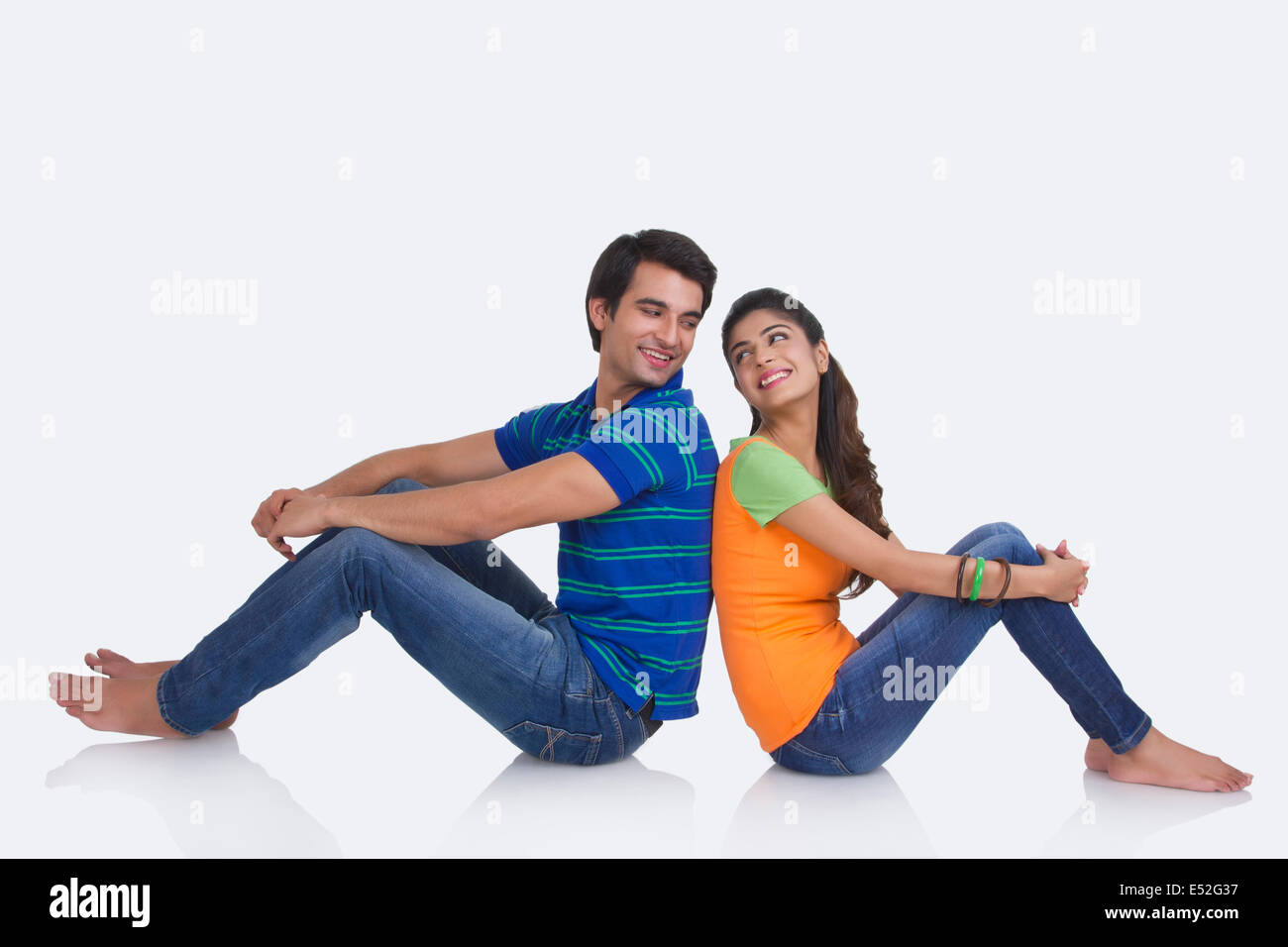 Full length side view of young couple sitting back to back over white ...