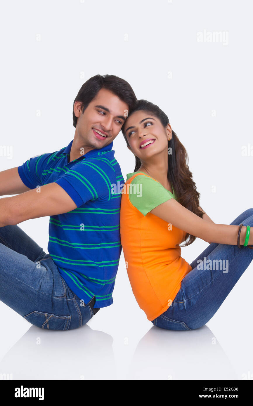 Loving young couple sitting back to back isolated on white background ...
