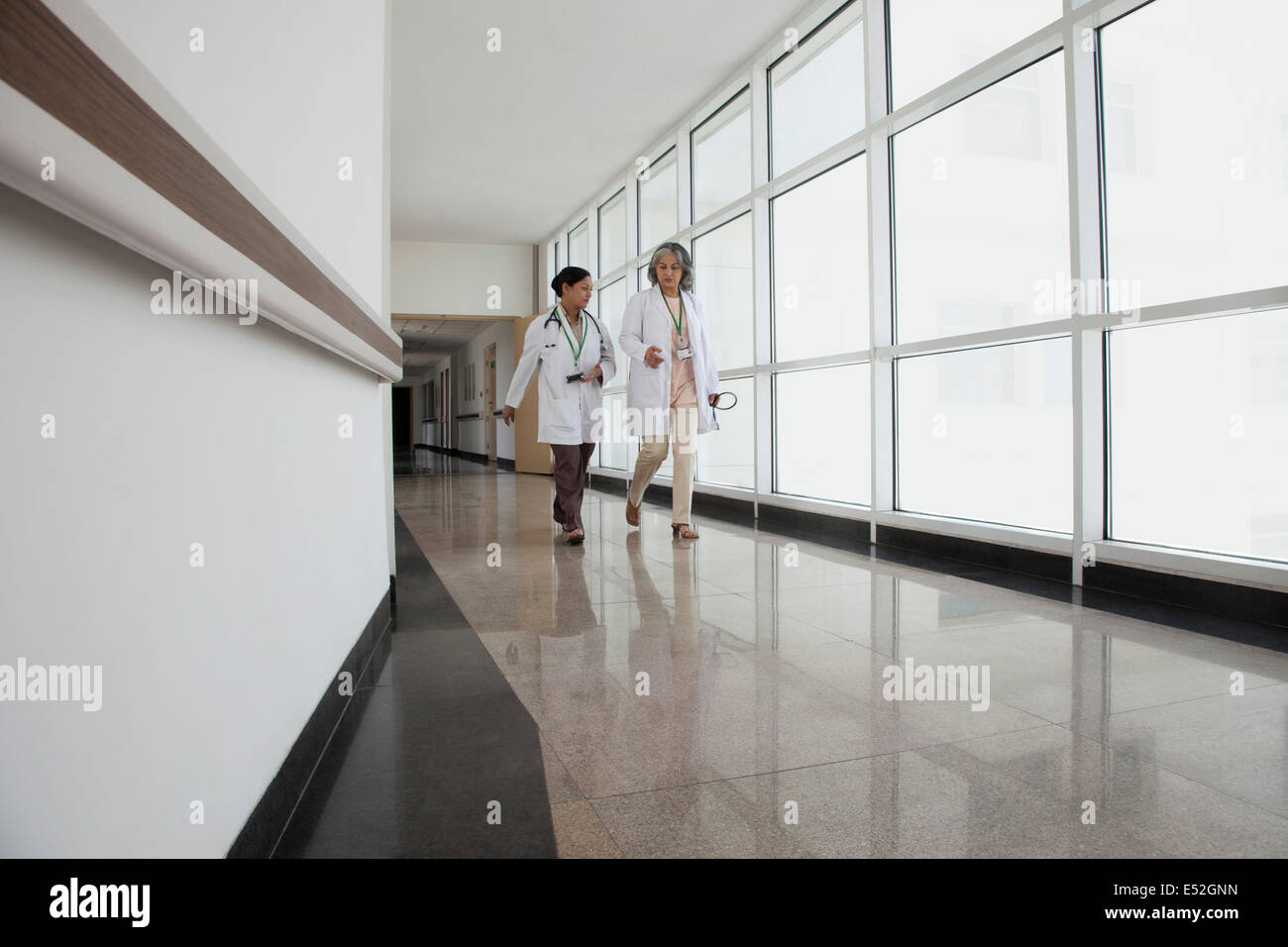 Two doctors in discussion walking down corridor Stock Photo - Alamy
