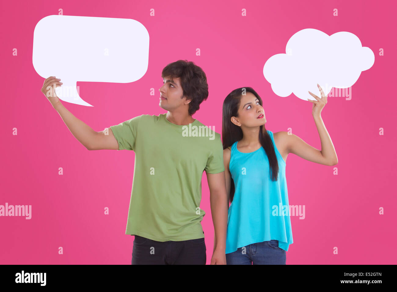 Young couple holding communication bubbles against pink background ...