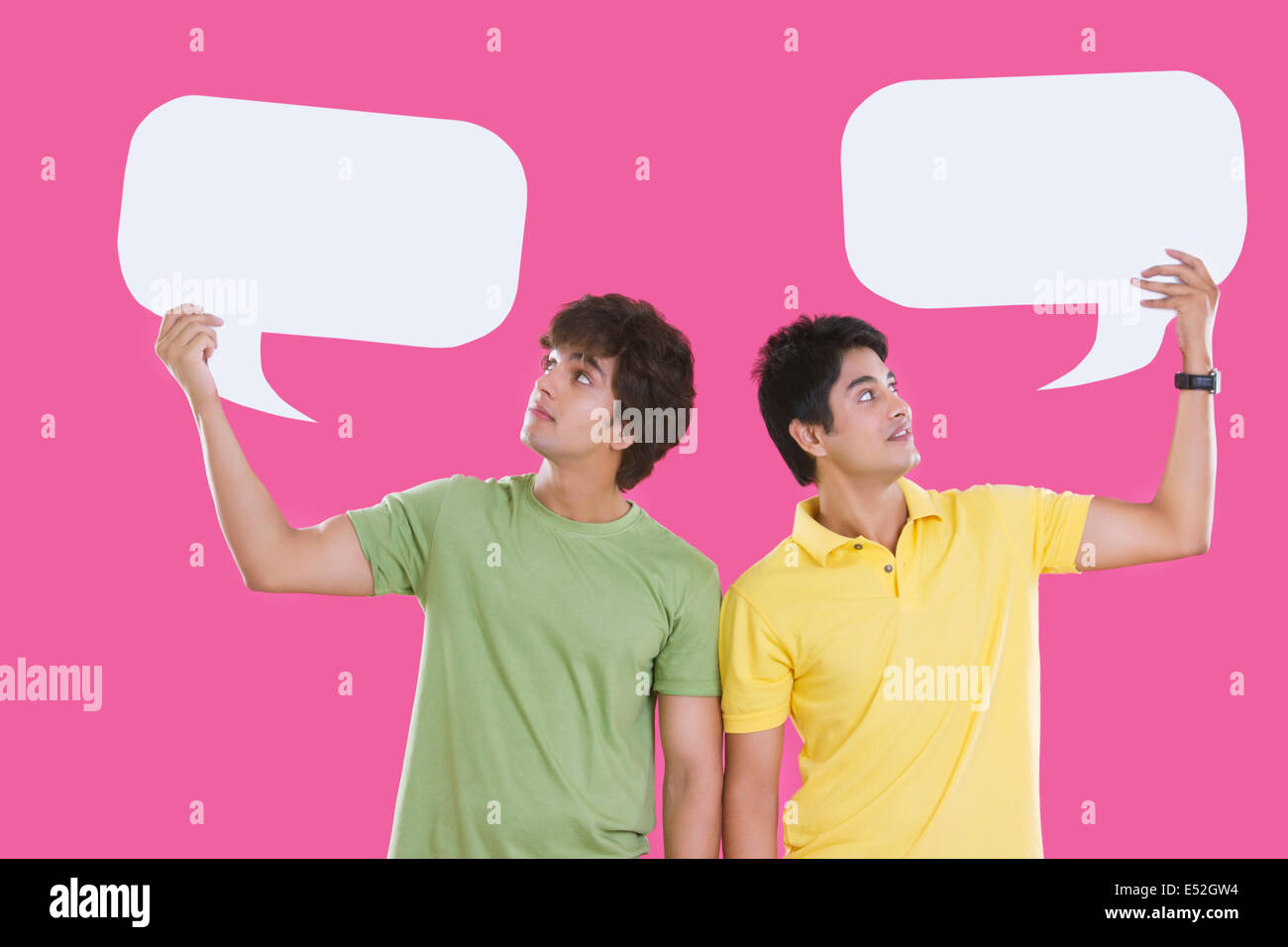 Young men holding speech bubbles isolated over pink background Stock ...