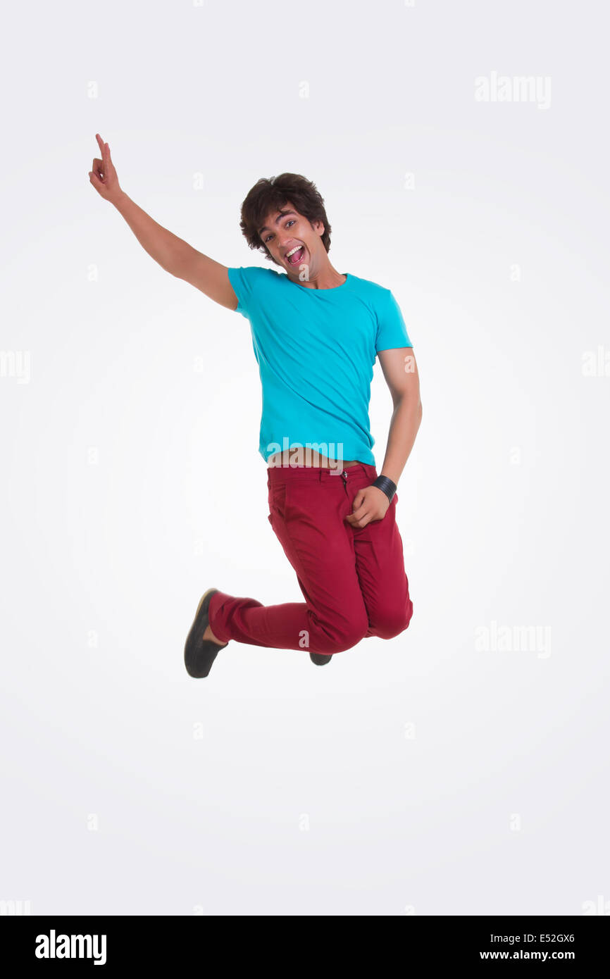 Full length portrait of cheerful young man jumping over white ...