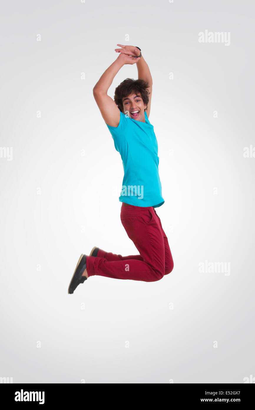 Full length side view of excited young man jumping over white ...