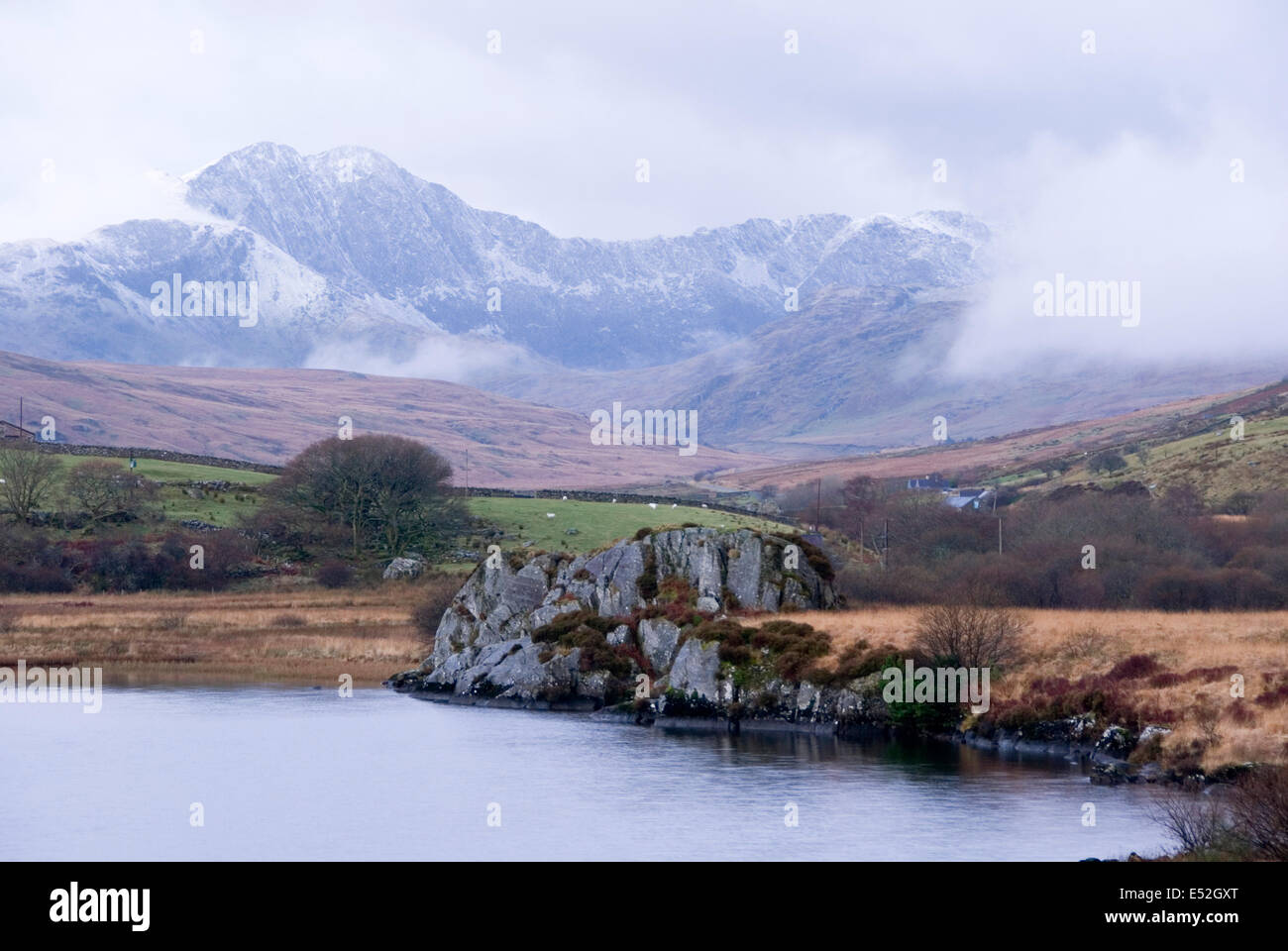 Snowdow viewed across the water of Capel Curig lake on a misty winter ...