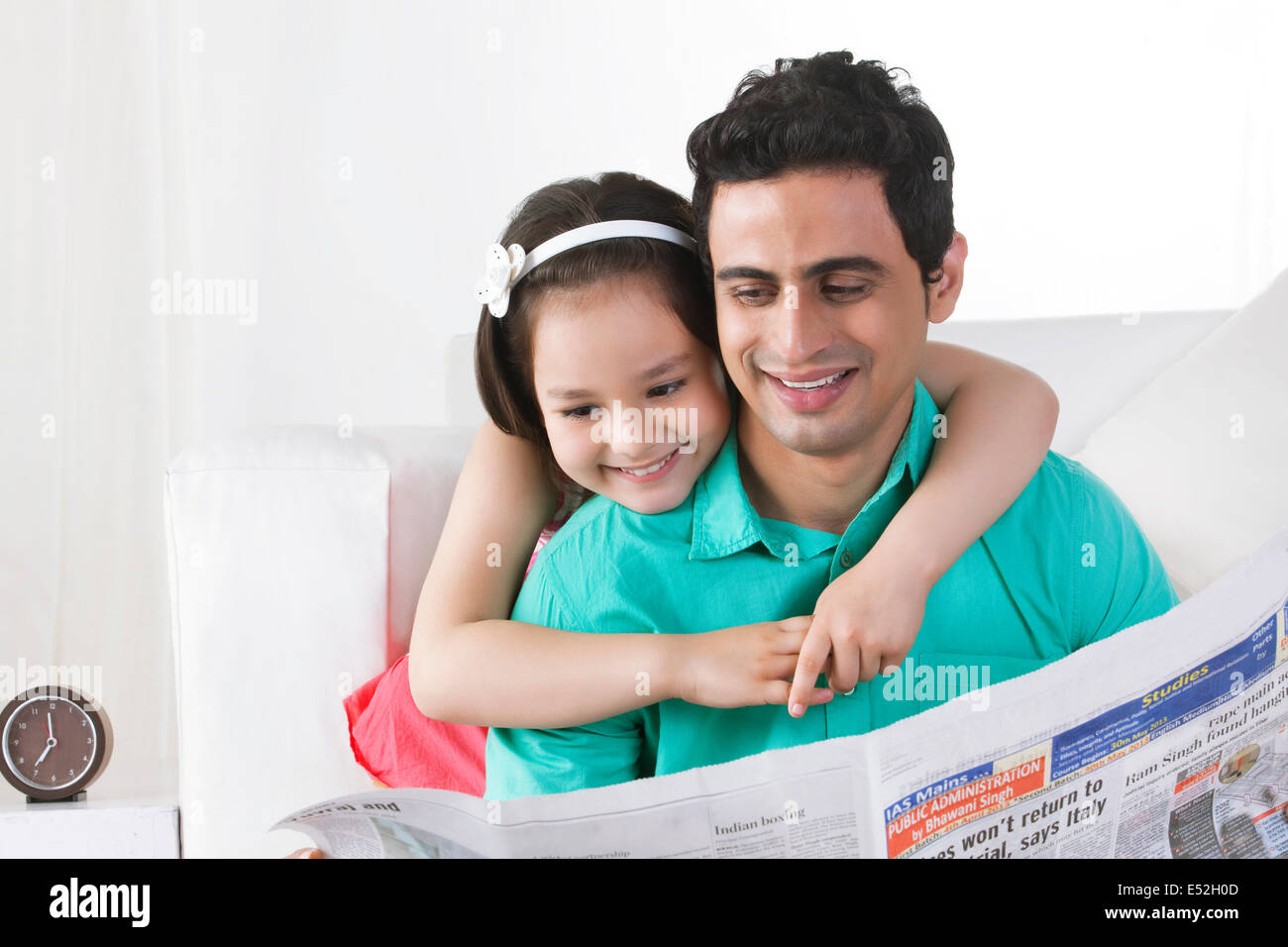 Loving cute girl and father reading newspaper in living room Stock ...