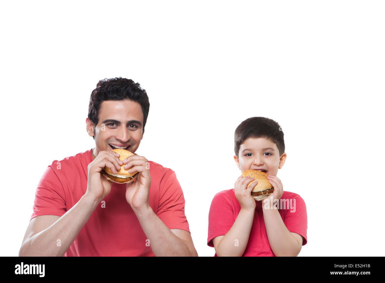Portrait of happy father and son eating burgers over white background ...