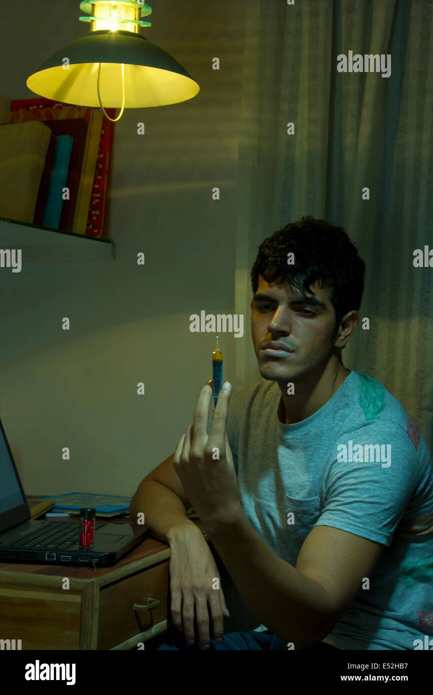 Young male drug addict holding syringe at home Stock Photo - Alamy