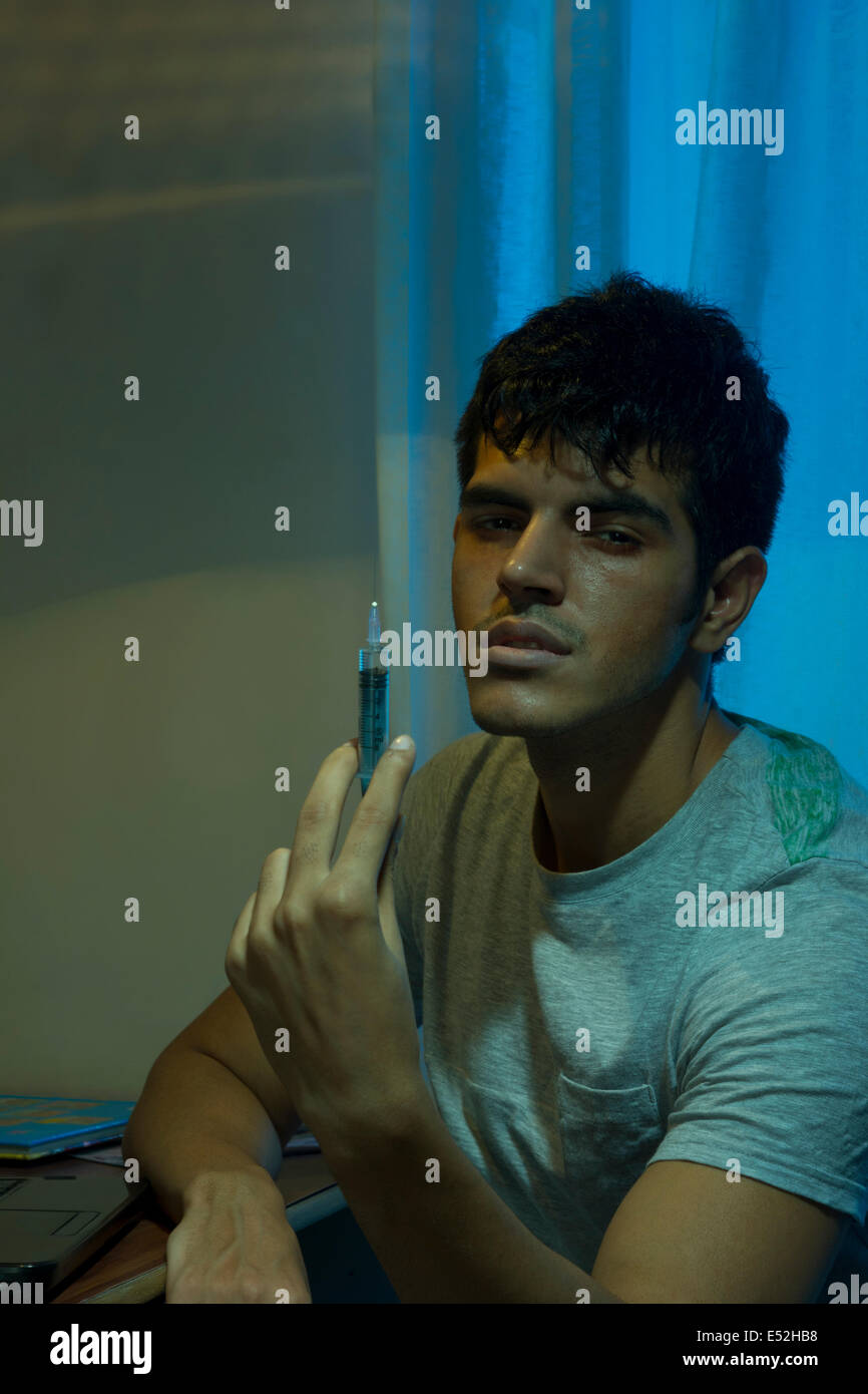 Portrait of male drug addict holding syringe at home Stock Photo - Alamy