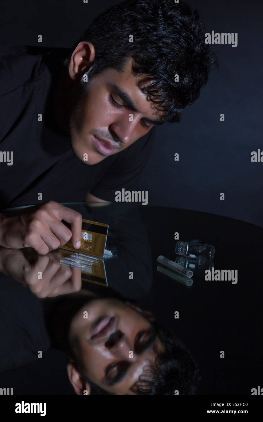 Male drug addict cutting cocaine with credit card on mirror Stock Photo ...