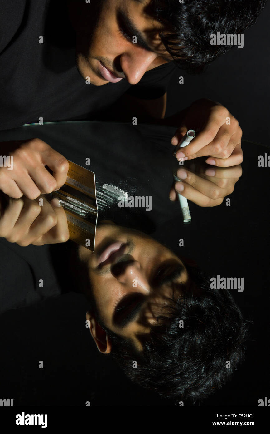 Drug addict cutting cocaine lines with credit card on mirror Stock ...