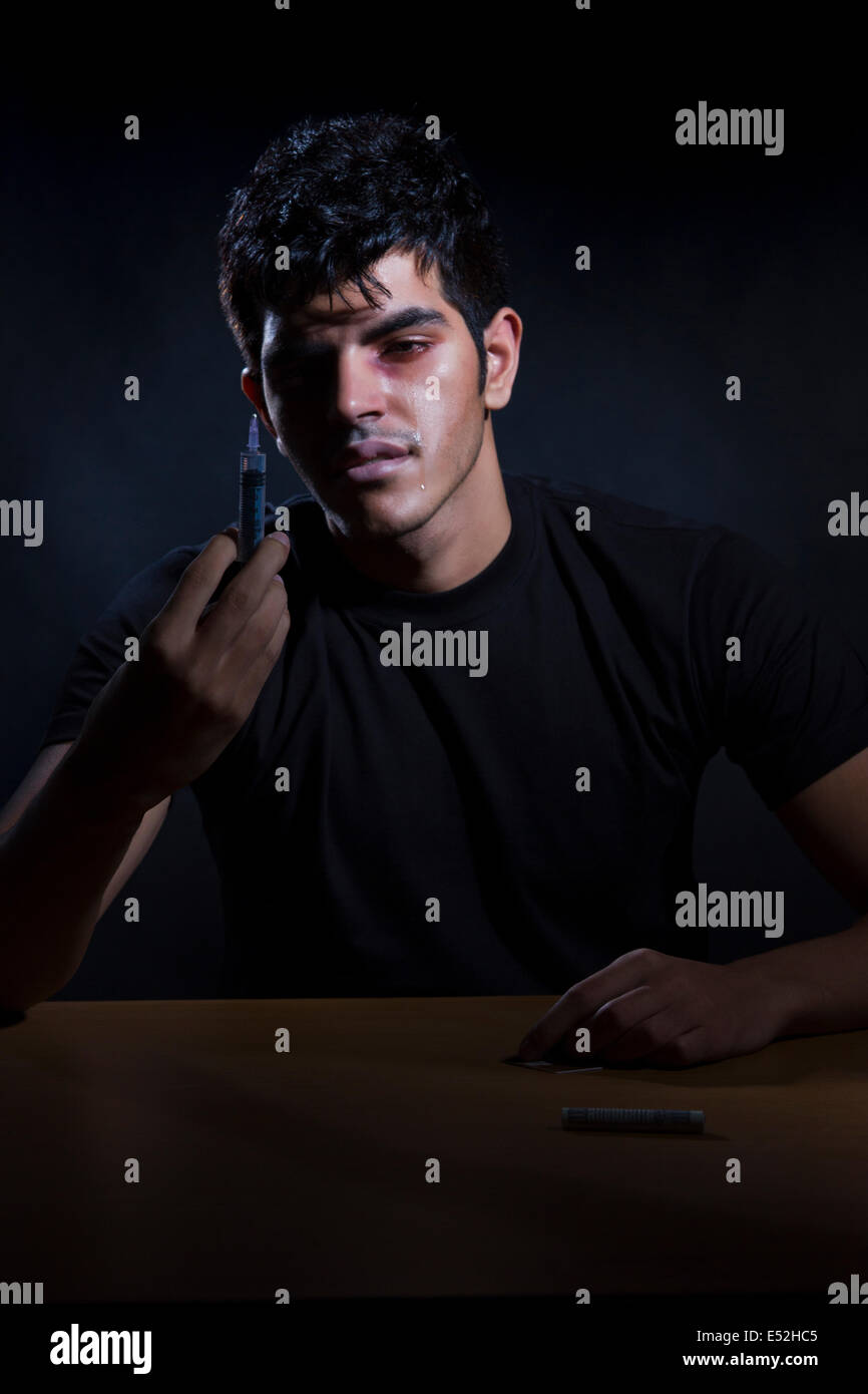 Depressed male drug addict looking at syringe Stock Photo - Alamy