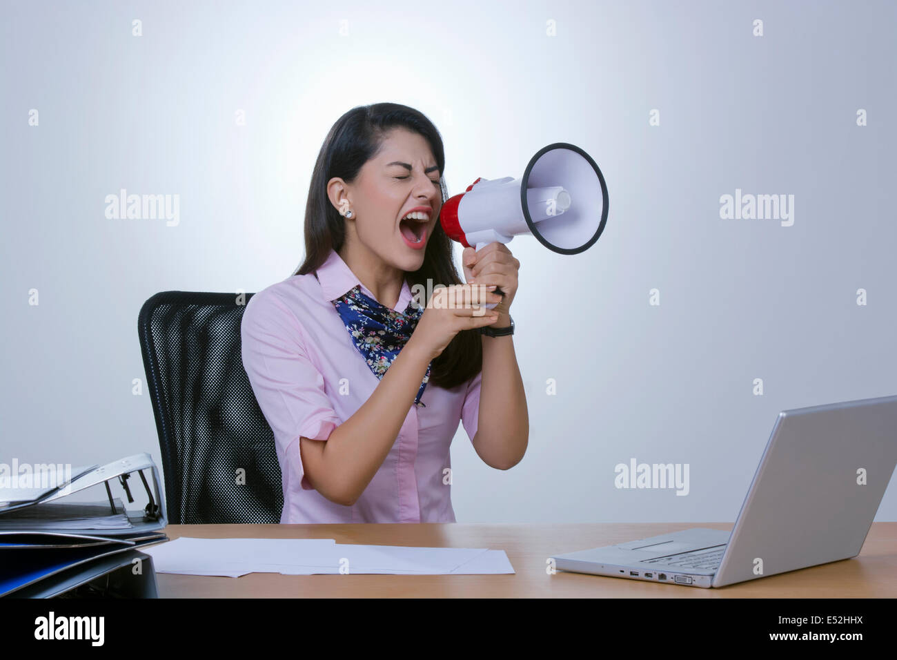 Frustrated businesswoman yelling in megaphone at office desk Stock ...