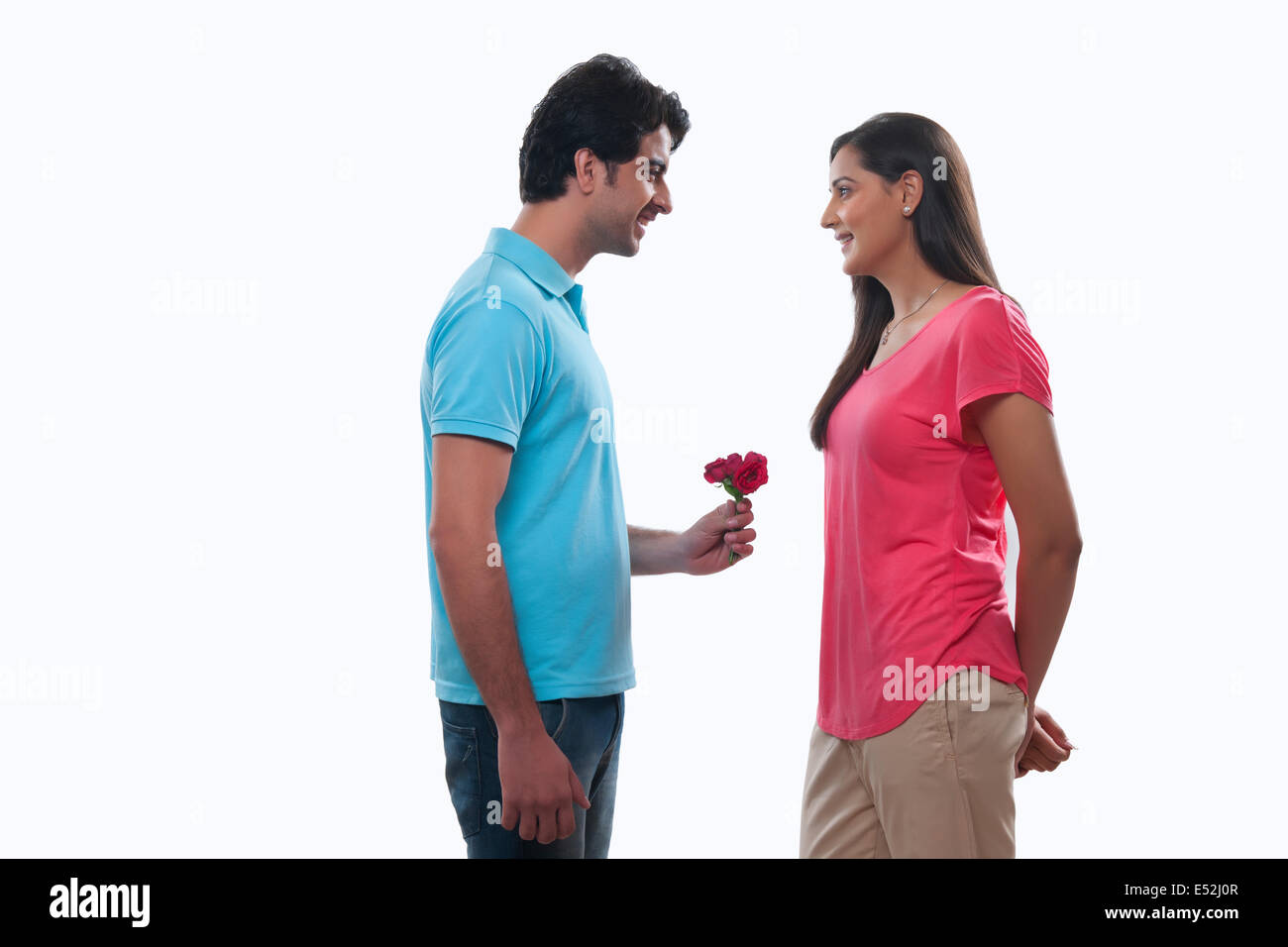 Happy young man giving rose to woman against white background Stock ...
