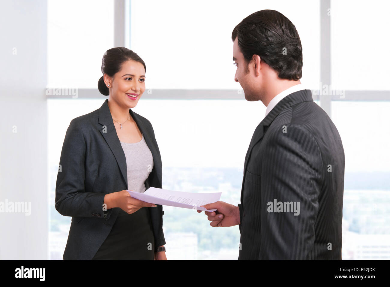 Smiling businesswoman receiving document from colleague in office Stock ...