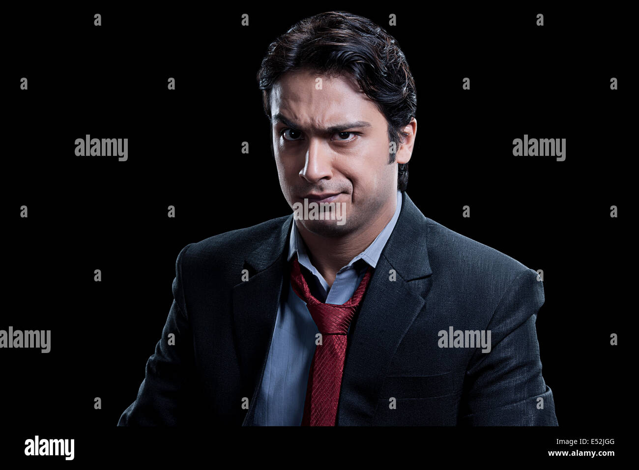 Portrait of suspicious businessman against black background Stock Photo ...