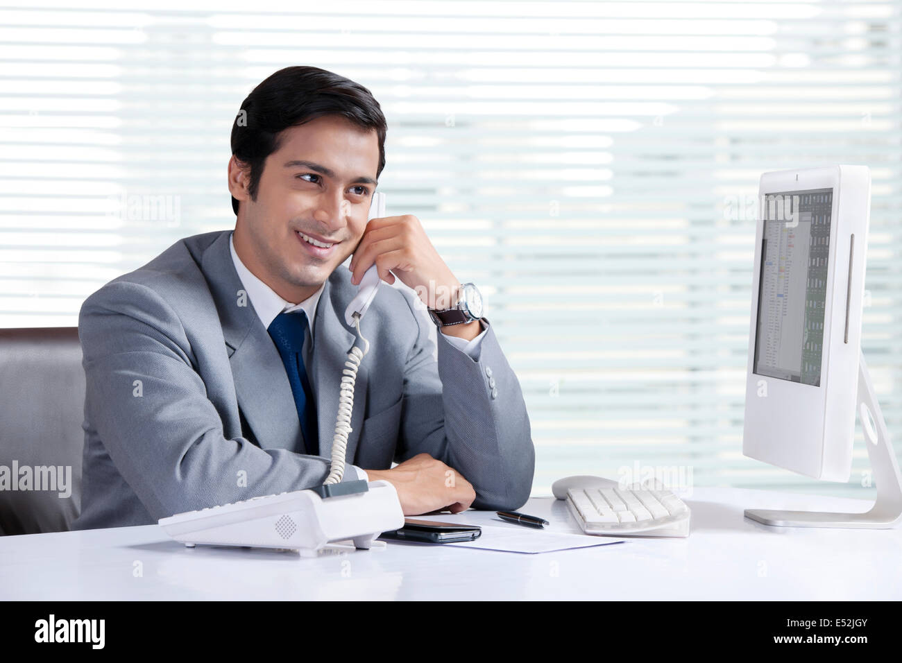Happy businessman answering telephone at office desk Stock Photo - Alamy
