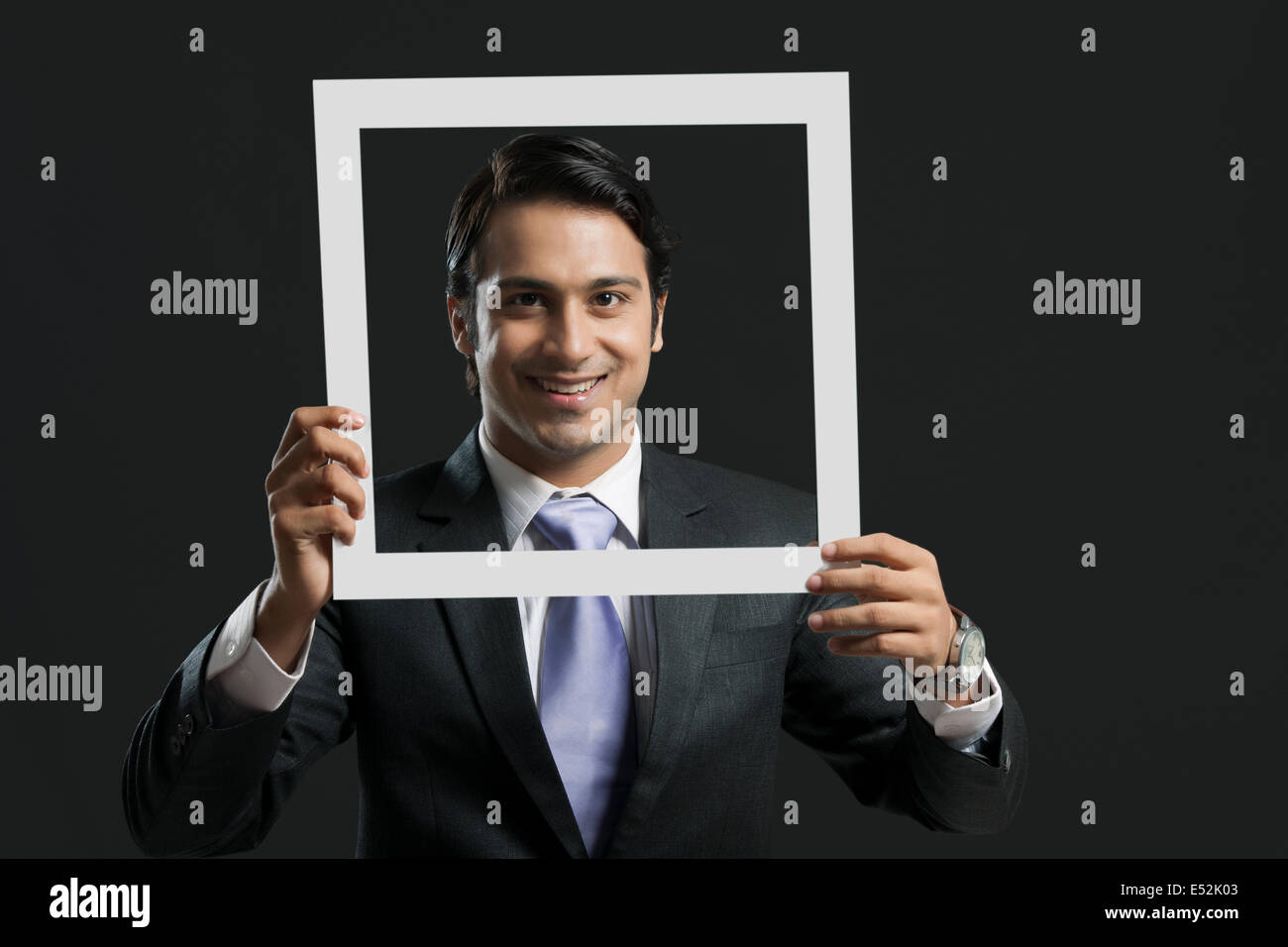 Portrait of happy businessman holding picture frame over black ...