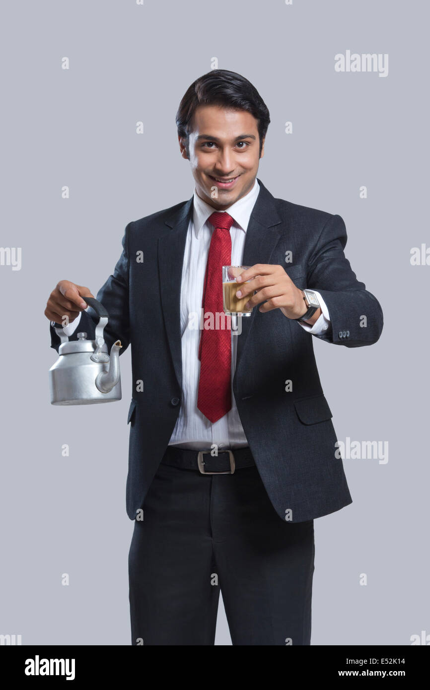 Portrait of smiling businessman offering tea over gray background Stock ...