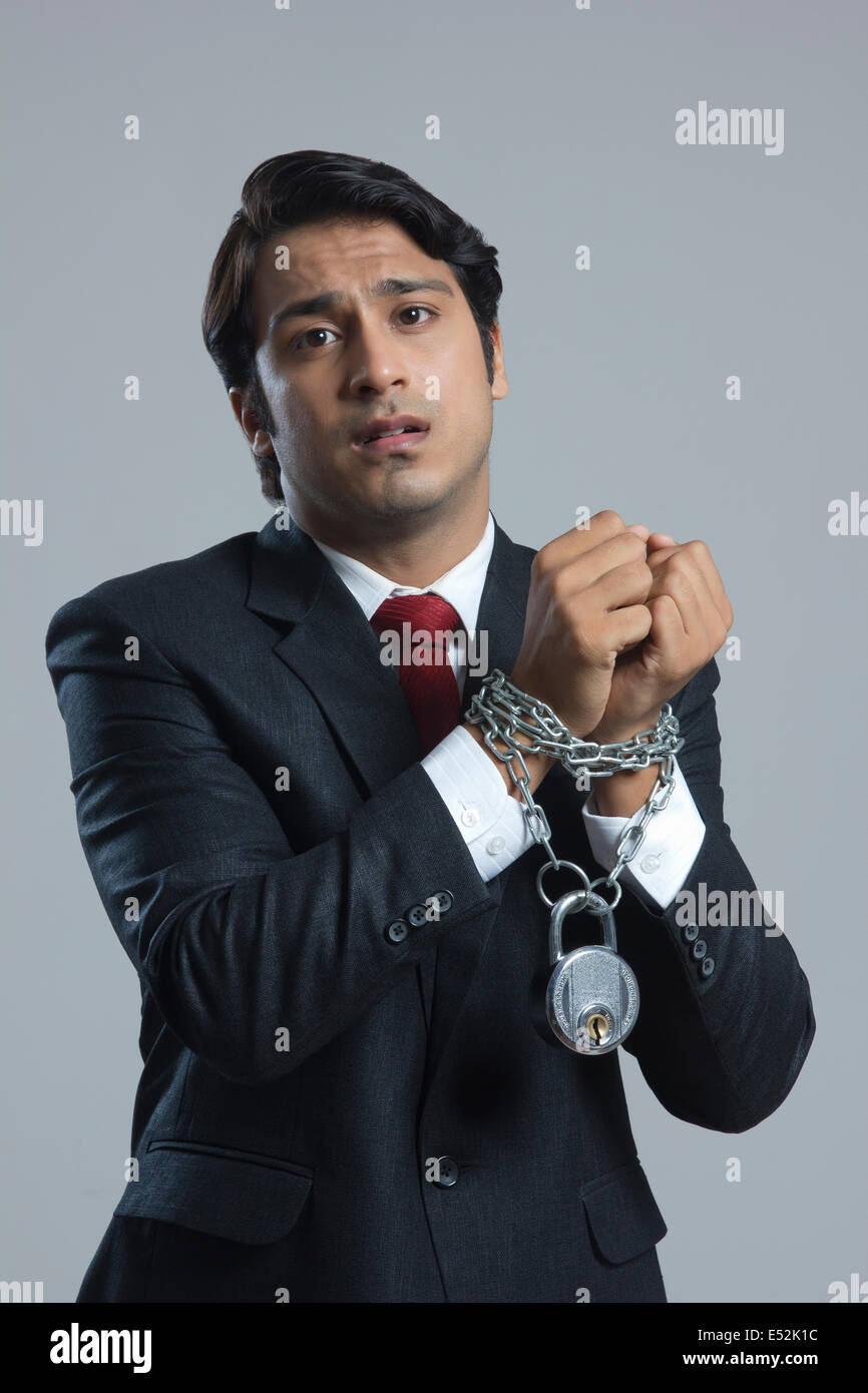 Portrait of sad businessman tied in chain against gray background Stock ...