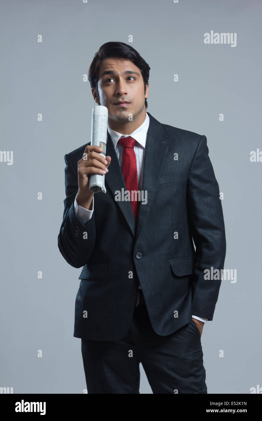 Confused businessman holding newspaper against gray background Stock ...