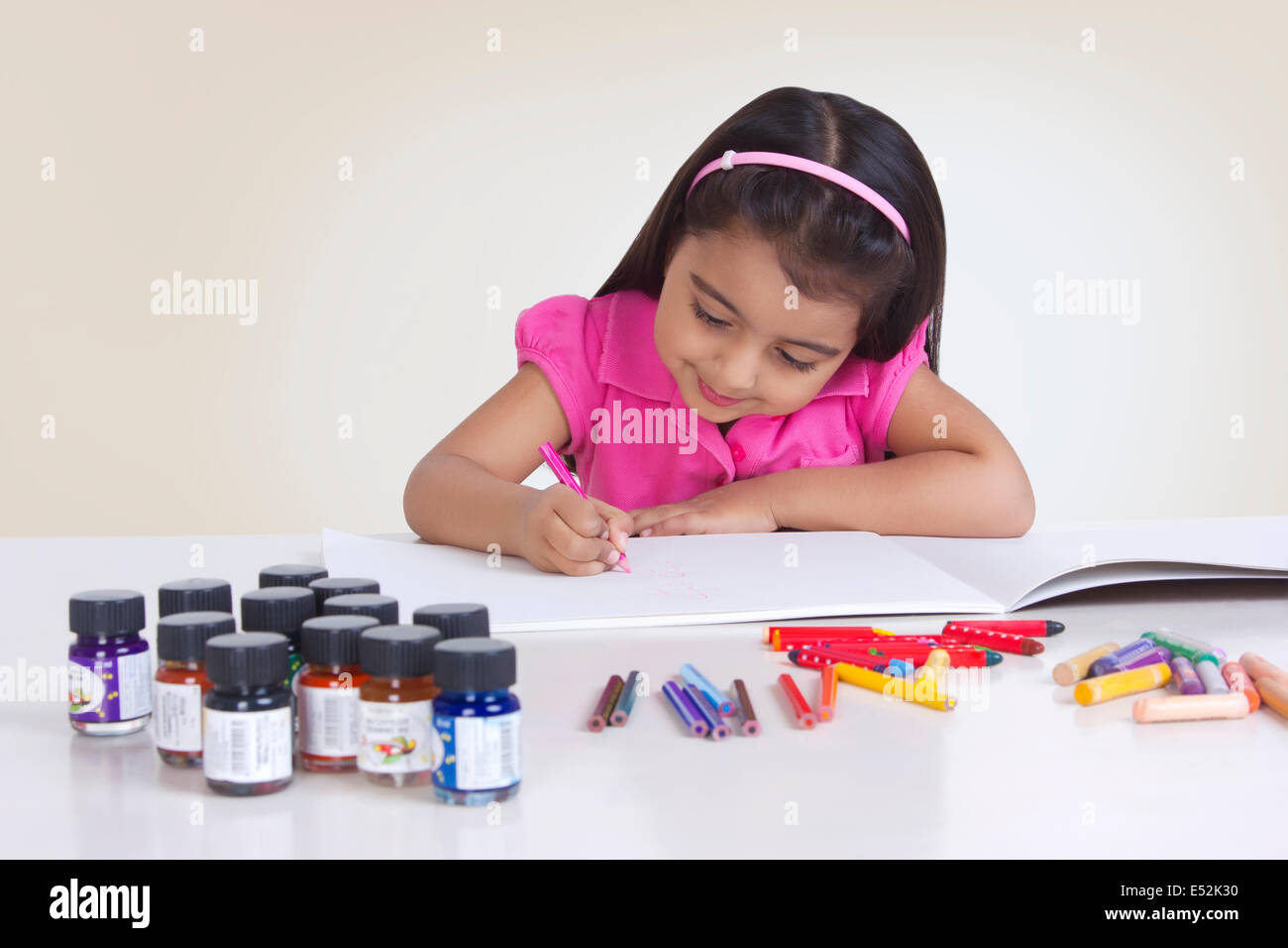 Girl coloring at table against white background Stock Photo - Alamy