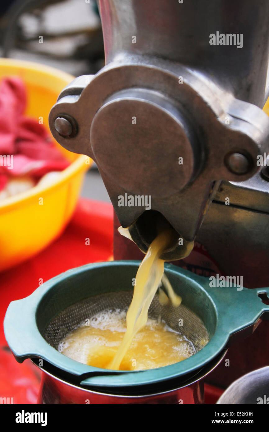 Juicer discharging lime juice in container Stock Photo - Alamy
